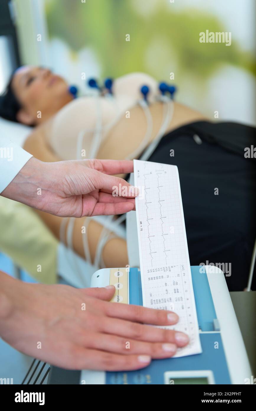 A caregiver is attentively checking a patients vitals with an EKG ...