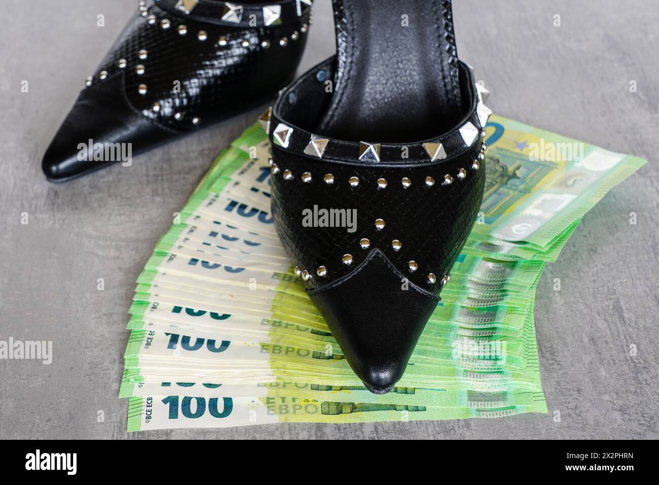 Black women's shoe with shiny metal spikes on many hundred euro bills ...