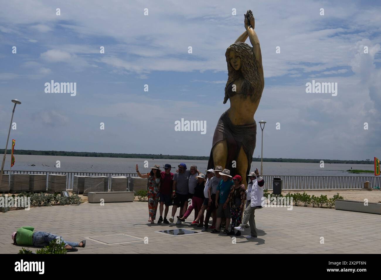 Tourists pose for photos in front of a statue of Colombian pop singer ...