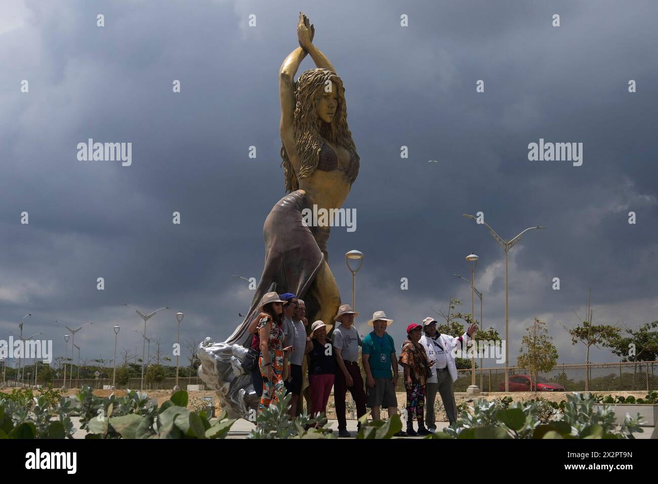 Tourists pose for photos in front of a statue of Colombian pop singer ...