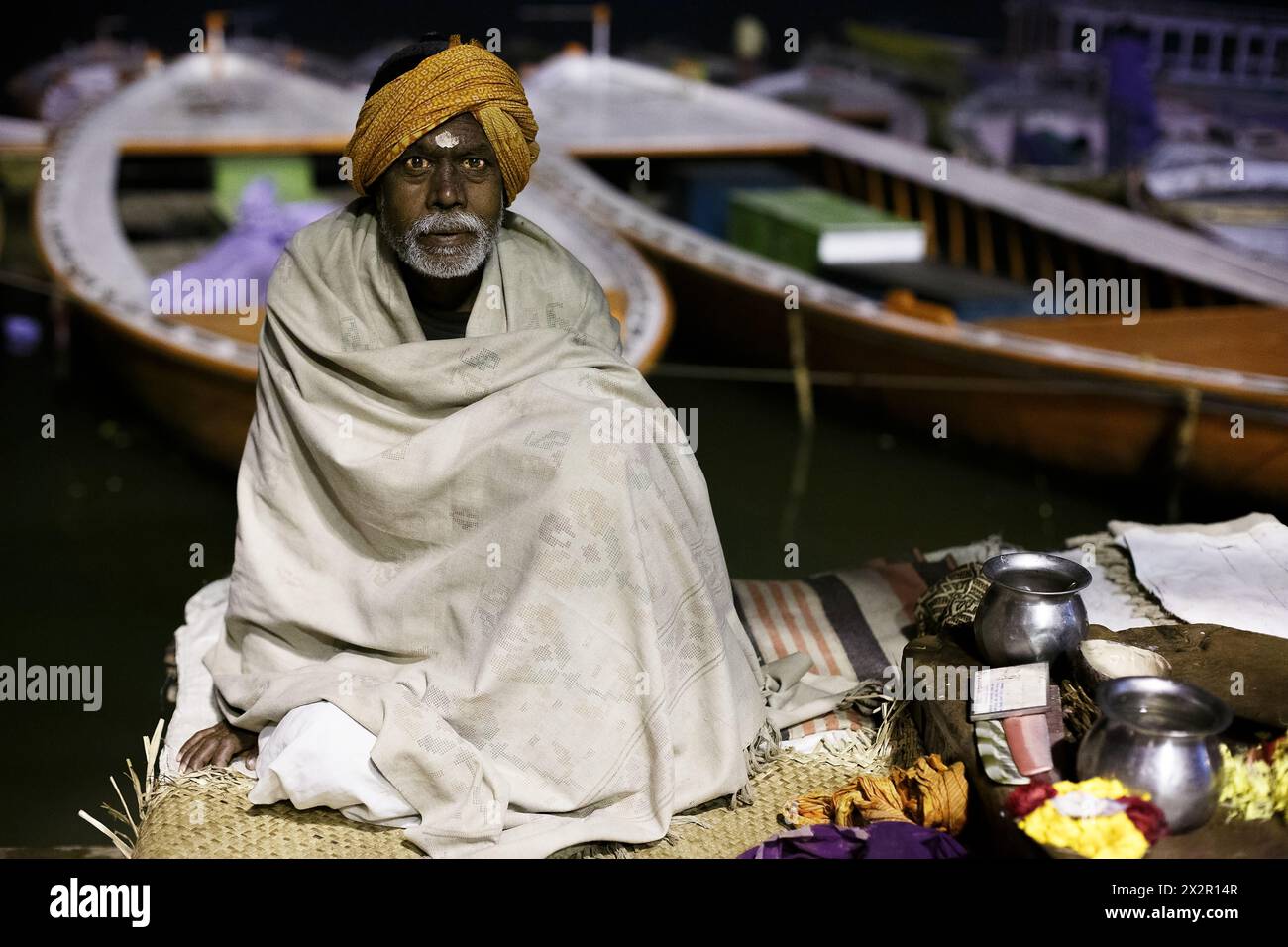 Hindu priest on a platform next to the Ganges River in the predawn at ...