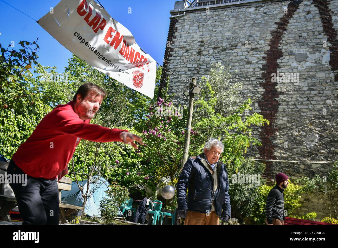 Players compete in petanque (boules game) beneath a placard reading ...