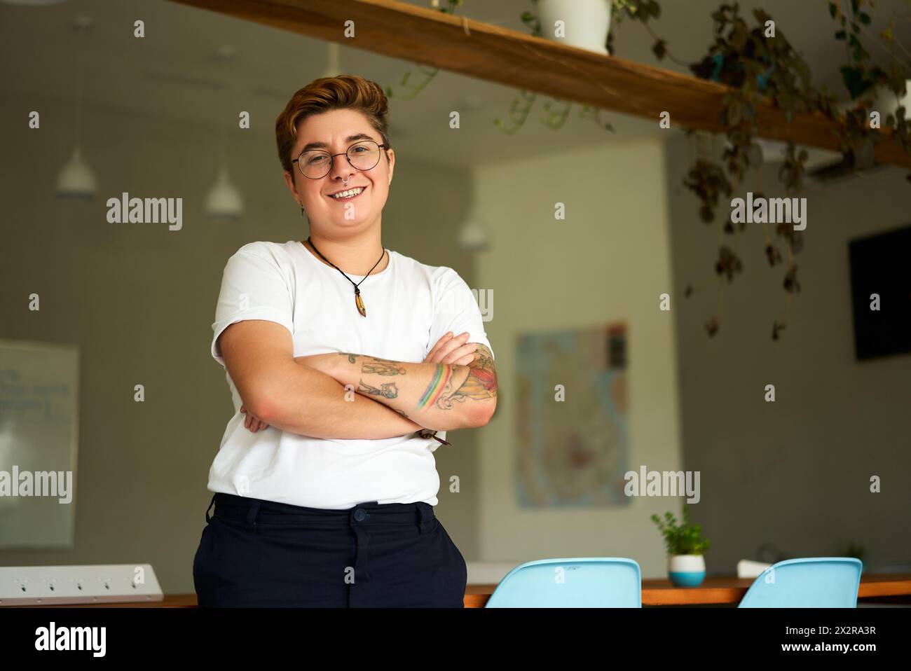 Confident Gen Z individual with tattoos stands in modern office ...
