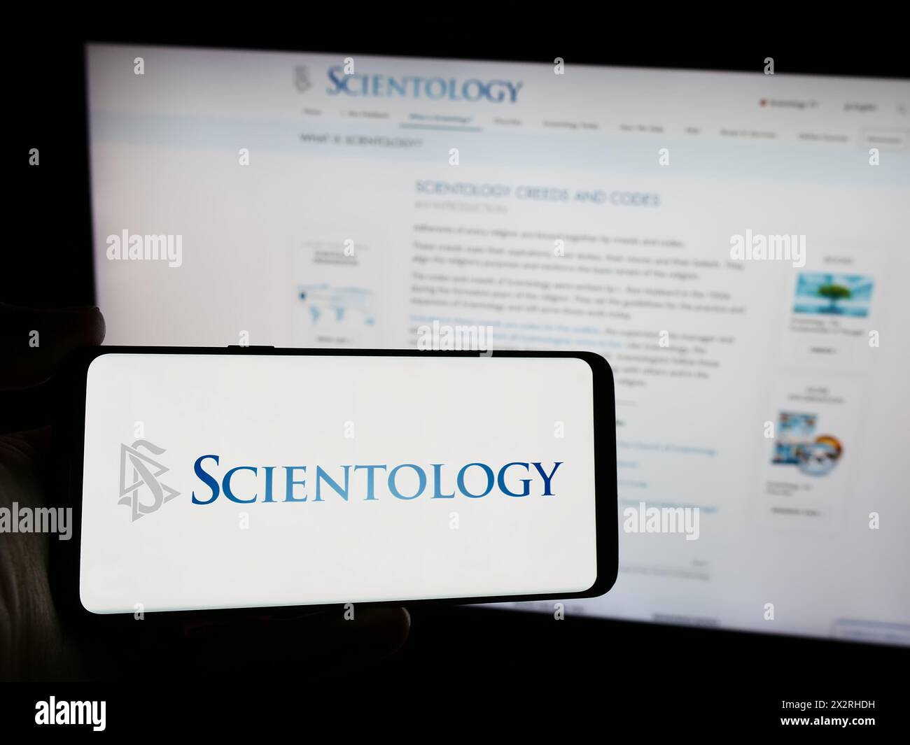 Person holding smartphone with logo of religious organisation ...