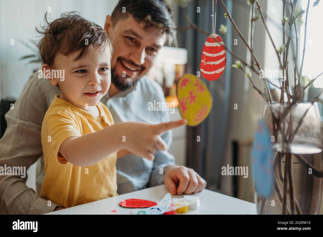 Happy father with son touching cardboard Easter eggs on twigs Stock ...