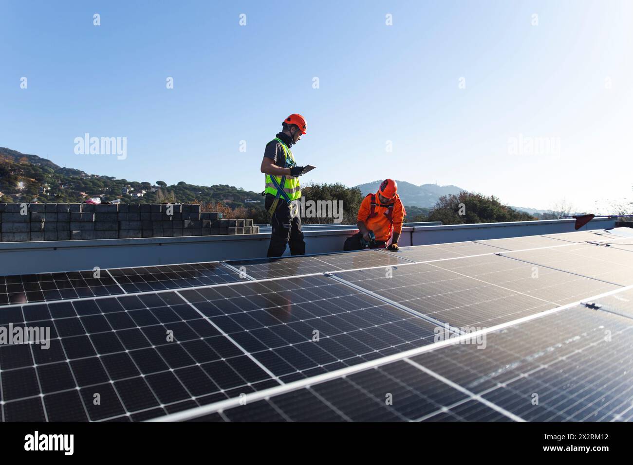 Technicians installing solar panels on rooftop Stock Photo - Alamy