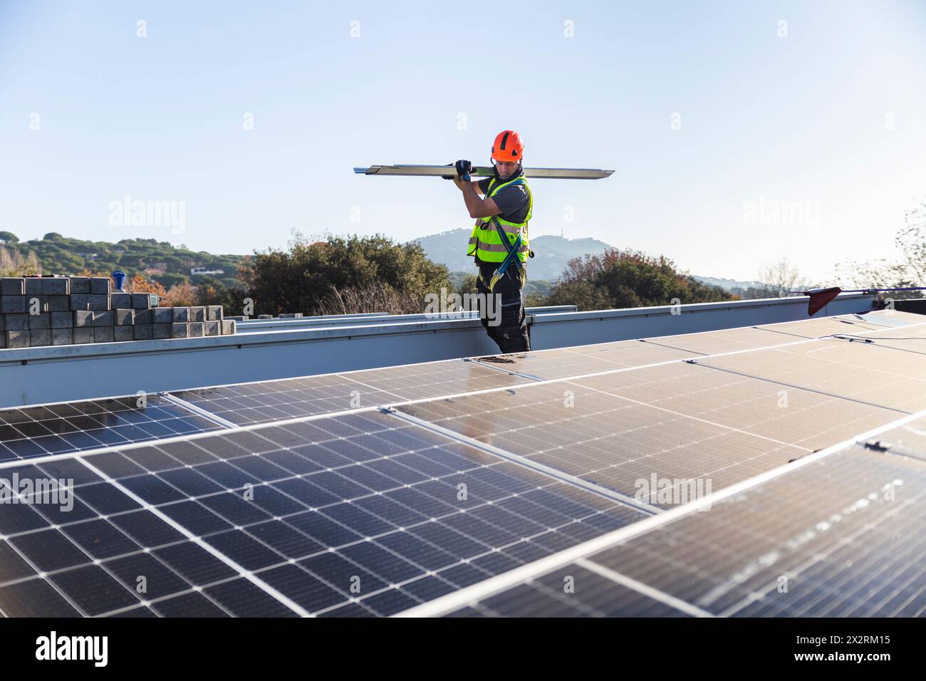 Solar technician carrying equipment by panels on rooftop Stock Photo ...