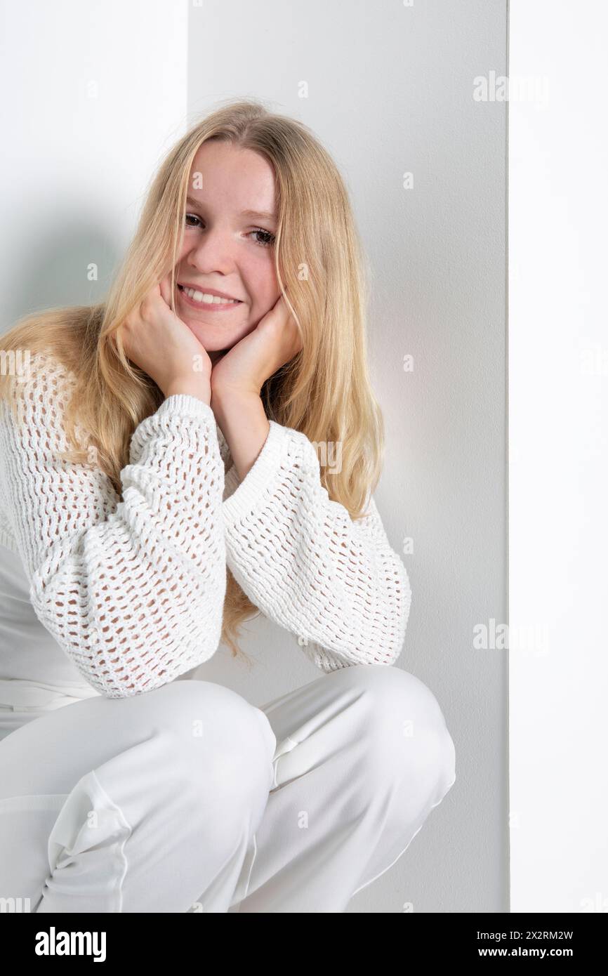 Teenage girl leaning on elbows against white background Stock Photo - Alamy