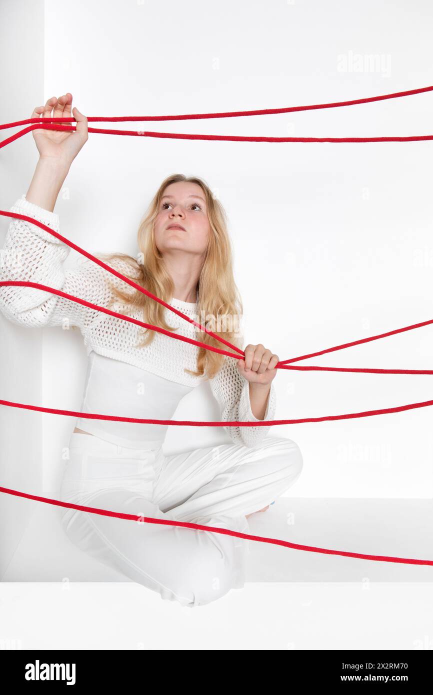 Teenager holding red thread against white background Stock Photo - Alamy