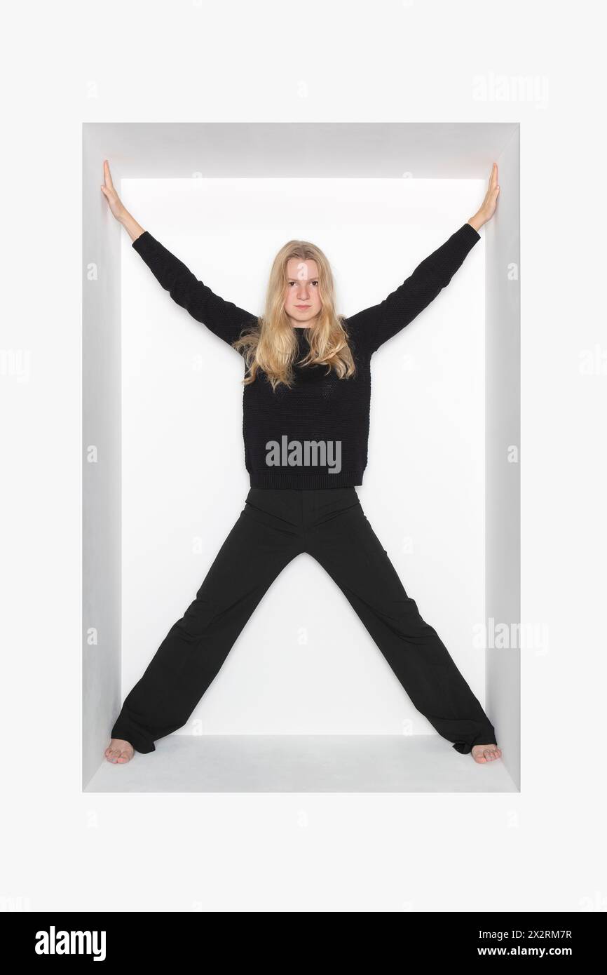 Teenage girl with arms raised and legs apart standing in alcove Stock ...