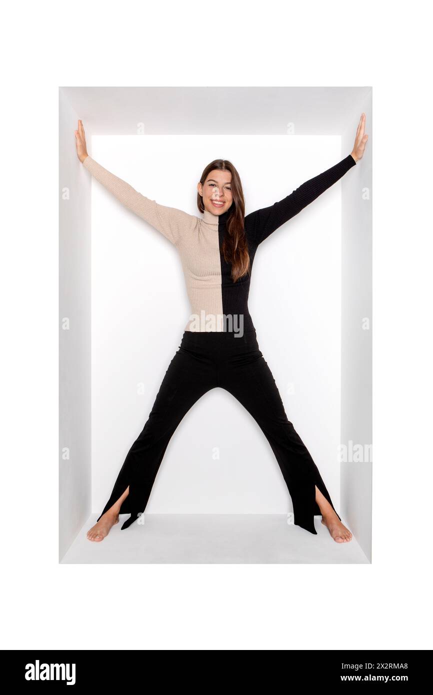 Smiling teenage girl with arms raised and legs apart standing in alcove ...
