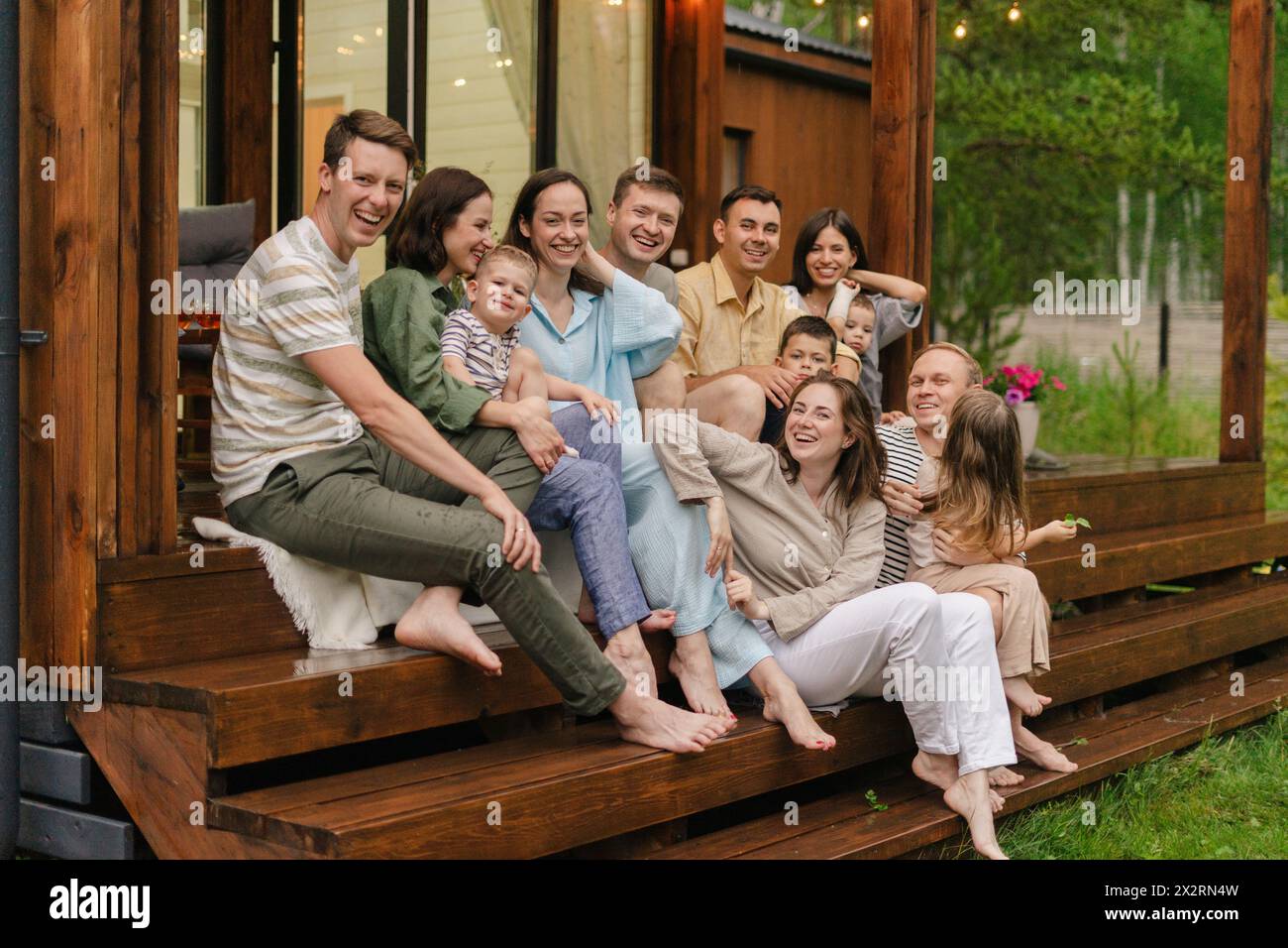 Cheerful family and friends sitting together on steps of house Stock ...