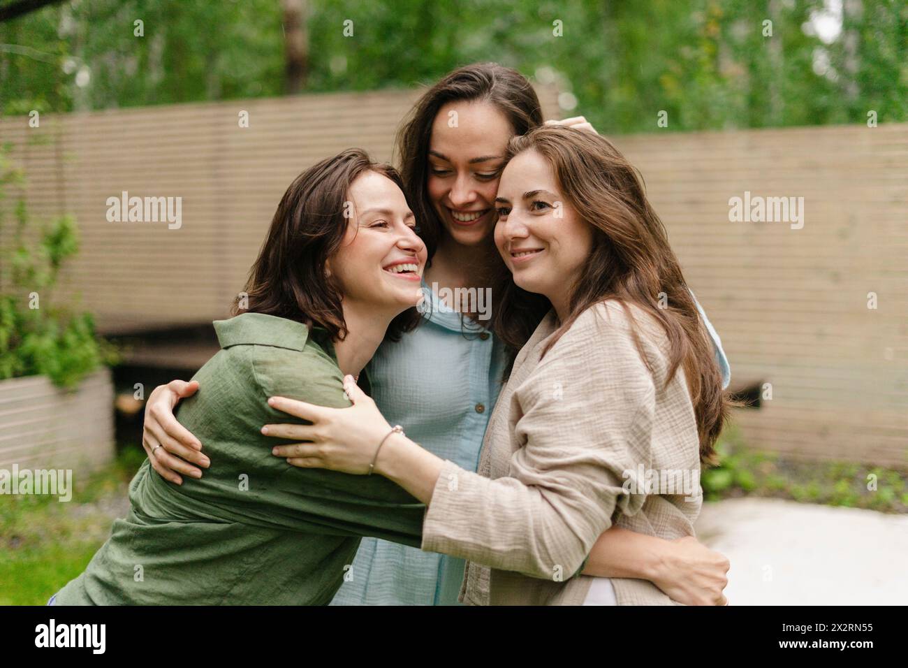 Happy friends embracing together in back yard Stock Photo - Alamy