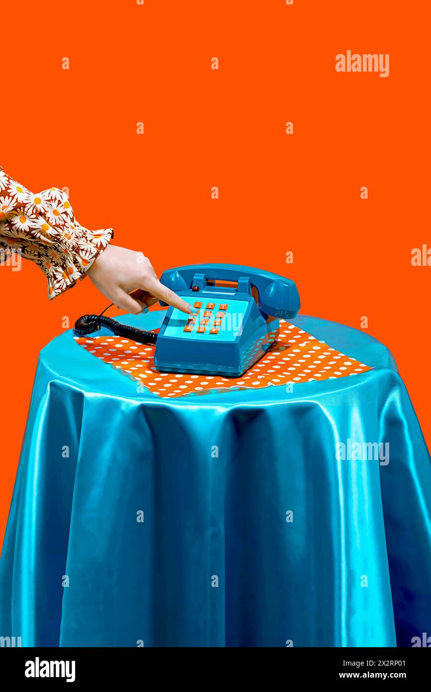 Hand of woman dialing on keypad of telephone against orange background ...