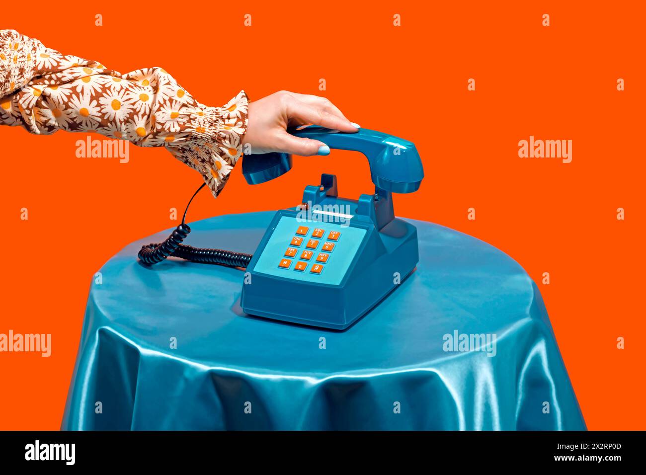 Woman picking up telephone receiver on table against orange background ...
