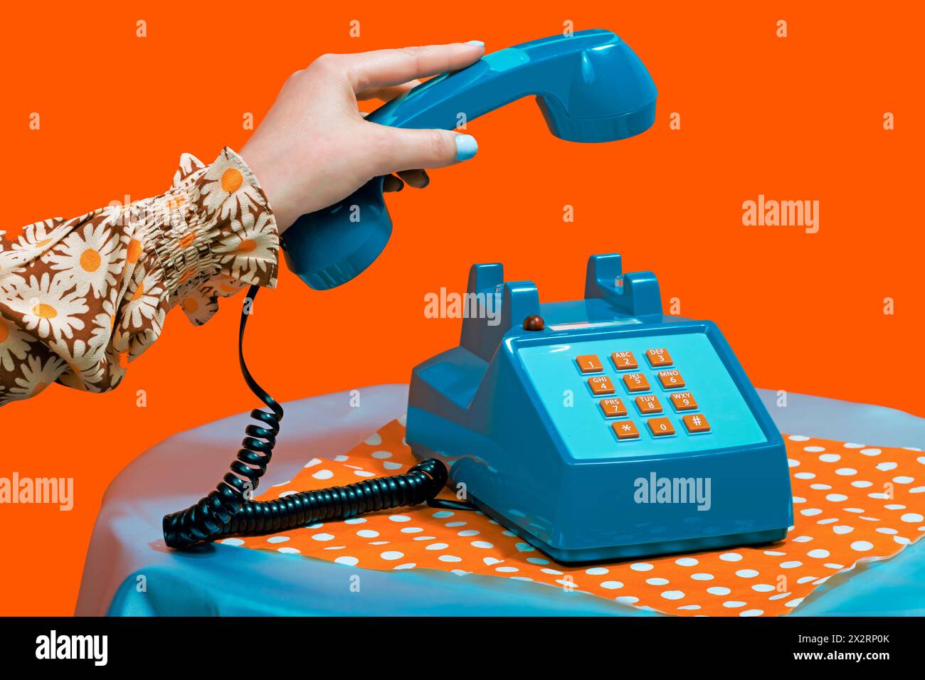 Hand of woman picking up telephone receiver against orange background ...