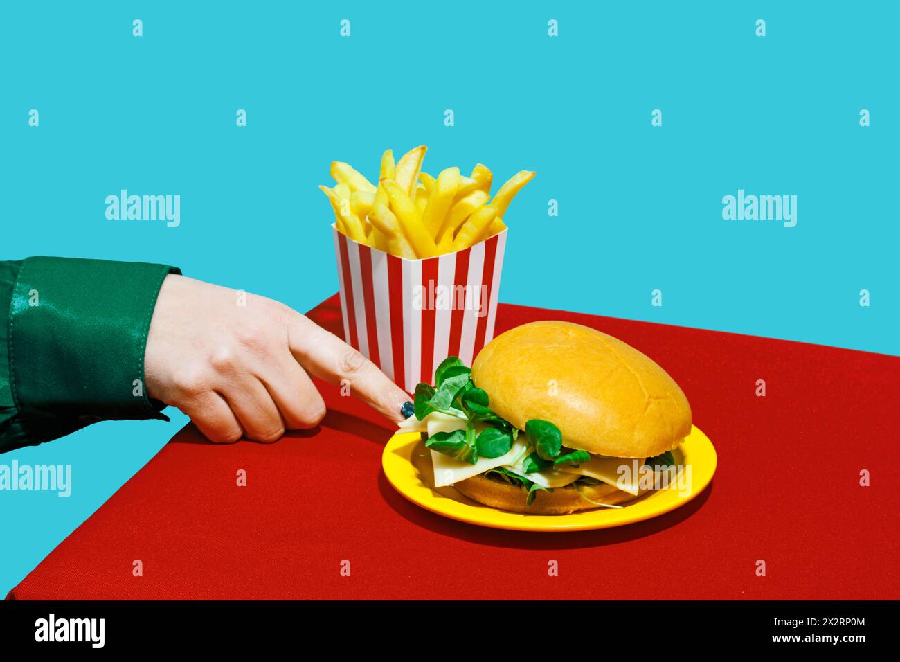 Hand of woman touching plate of cheeseburger on table against blue ...