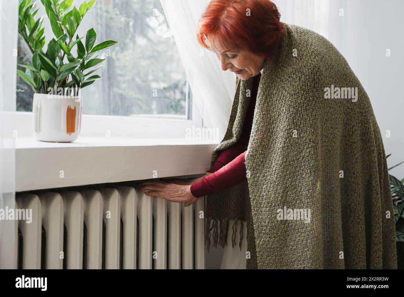 Senior woman examining temperature of radiator at home Stock Photo - Alamy