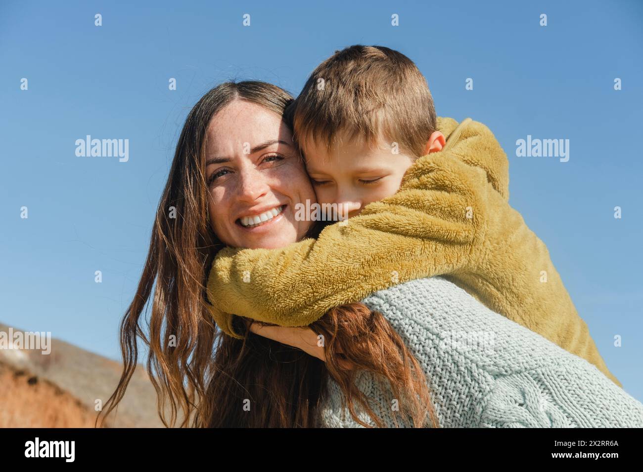 Son with arm around mother under clear sky Stock Photo - Alamy