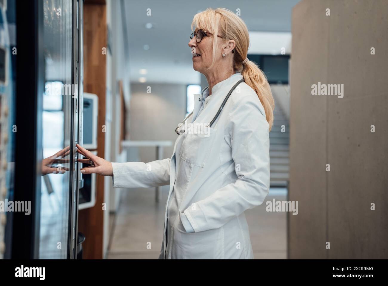 Smiling mature doctor standing in front of vending machine Stock Photo ...