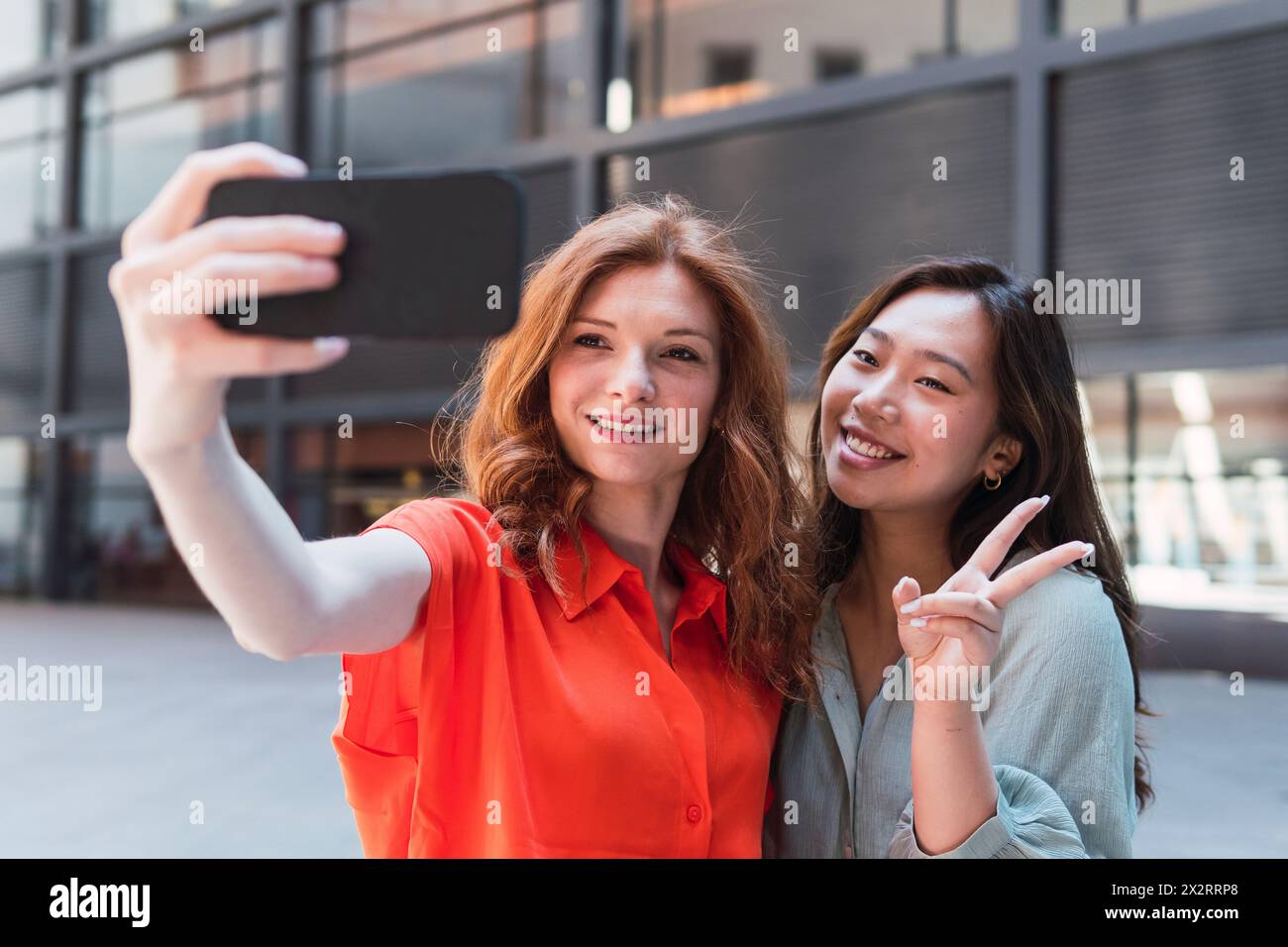 Woman taking selfie with friend making peace sign Stock Photo - Alamy
