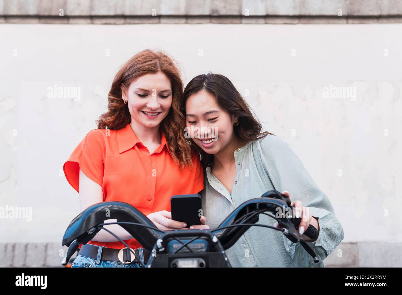 Smiling friends renting electric bicycle at station Stock Photo - Alamy
