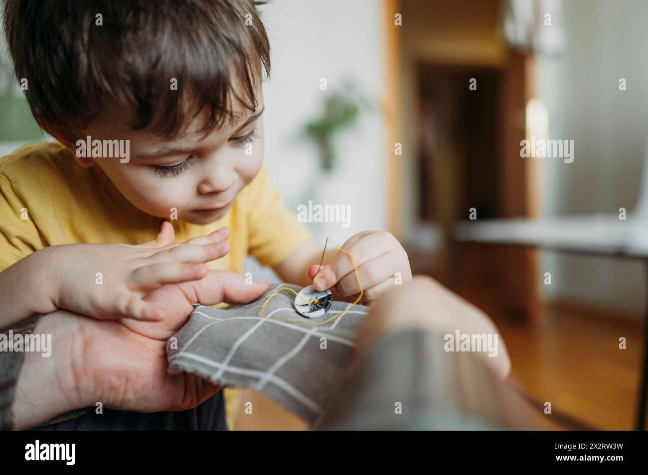 Father teaching son to sew button on gray colored cloth Stock Photo - Alamy