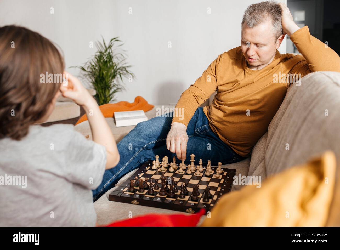 Father and son playing chess on sofa at home Stock Photo - Alamy
