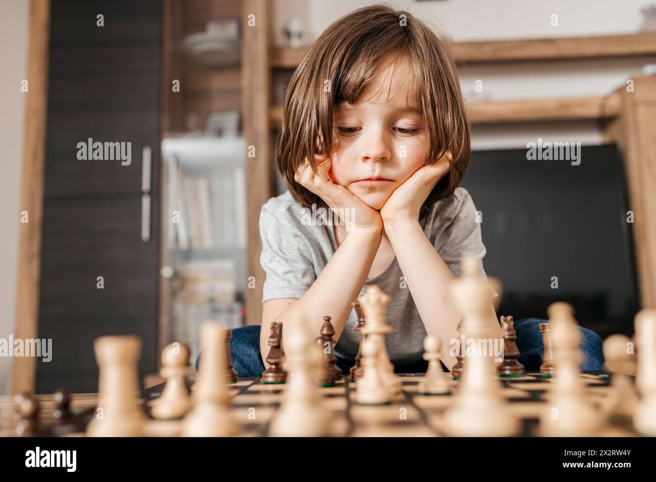 Thoughtful boy looking at chess pieces in home Stock Photo - Alamy