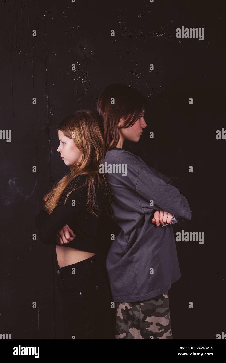 Angry friends standing back to back in front of black background Stock ...