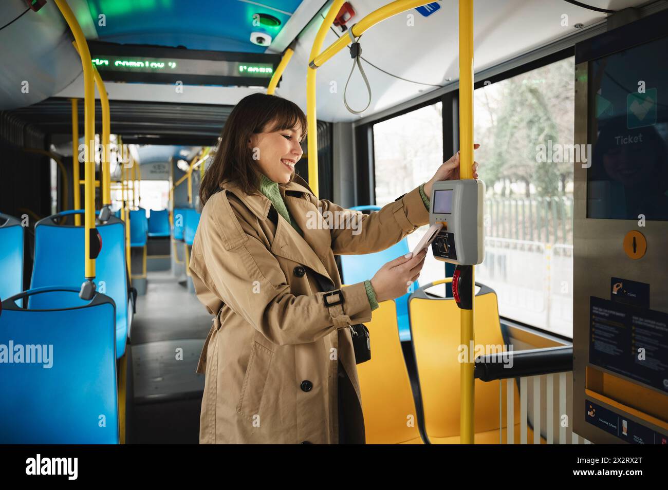 Happy passenger buying ticket in bus through contactless payment using ...