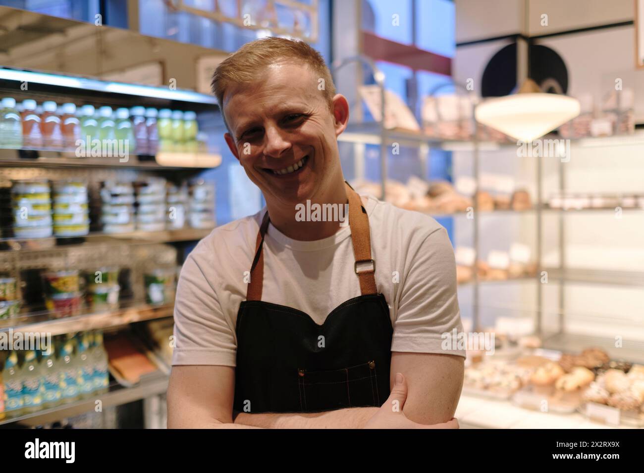Happy baker standing with arms crossed in store Stock Photo - Alamy
