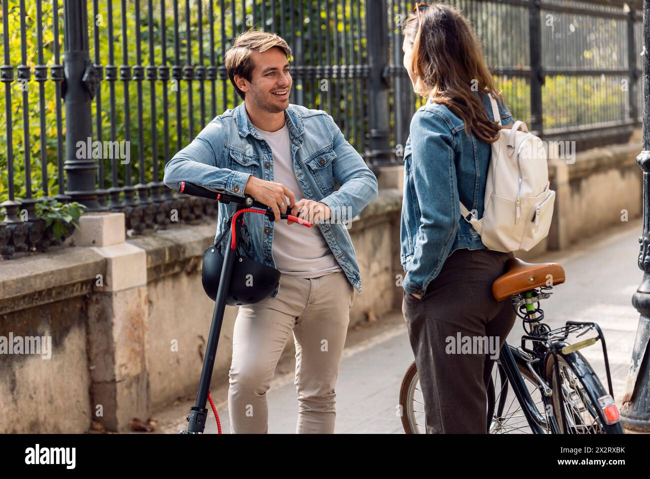 Man leaning on electric push scooter and talking to girlfriend at ...