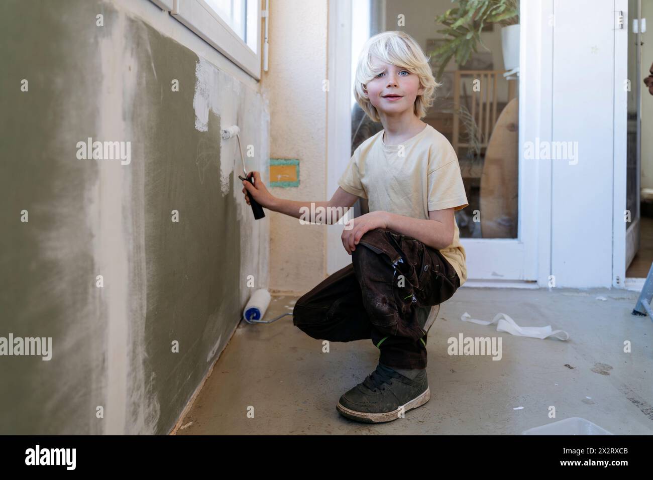 Boy crouching and painting wall at home Stock Photo - Alamy