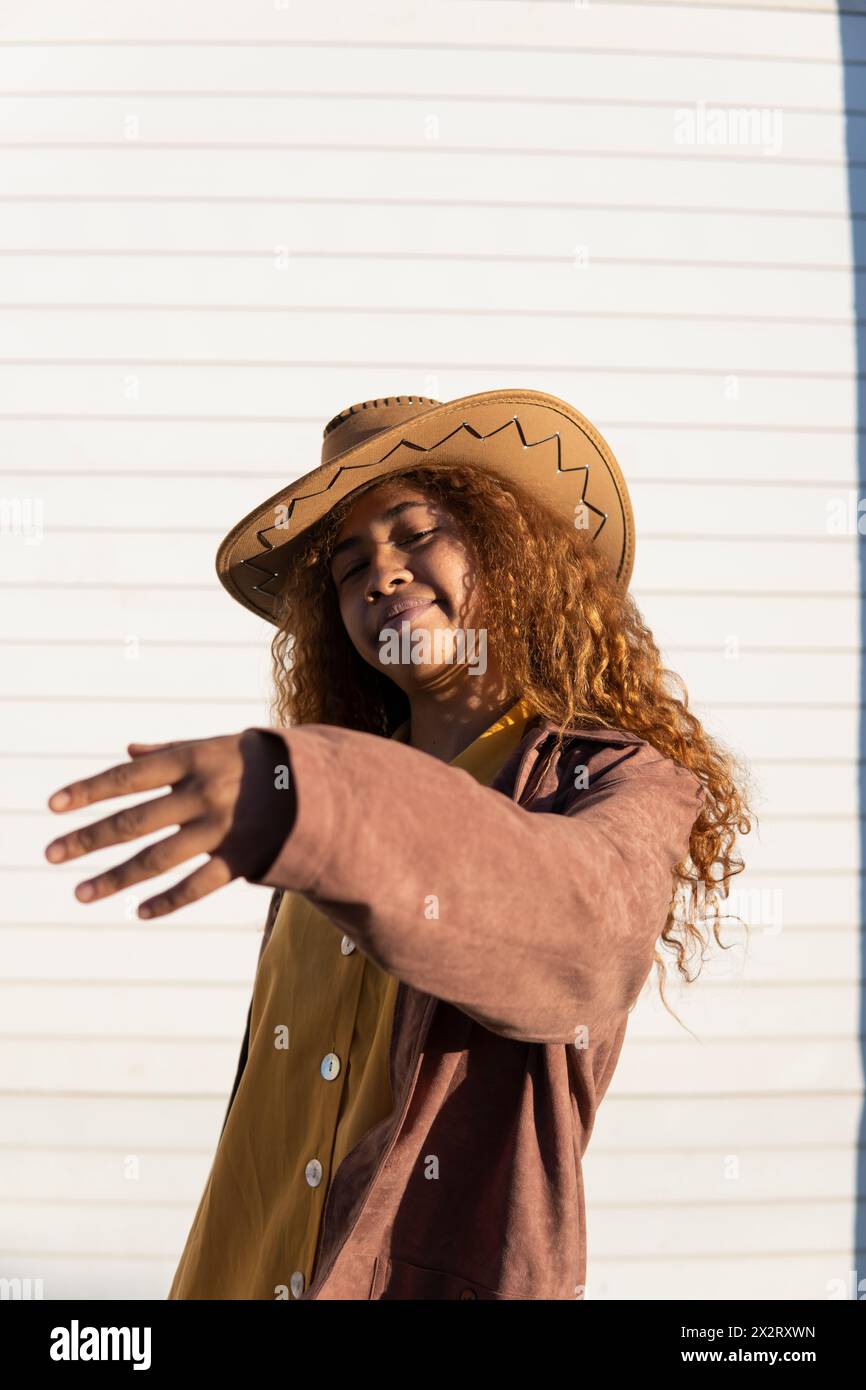 Smiling young woman with curly hair wearing jacket and cowboy hat Stock ...