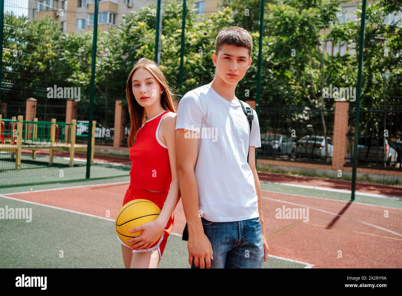 Basketball player standing with friend in schoolyard Stock Photo - Alamy