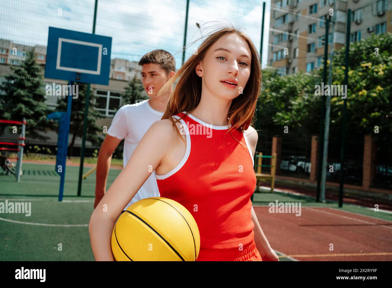 Basketball player walking with friend in background at school yard ...