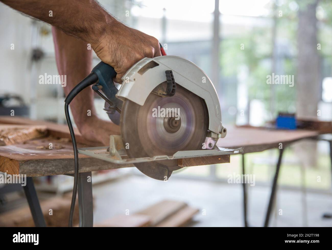 Carpenter cutting timber with electric circular saw at workshop Stock ...