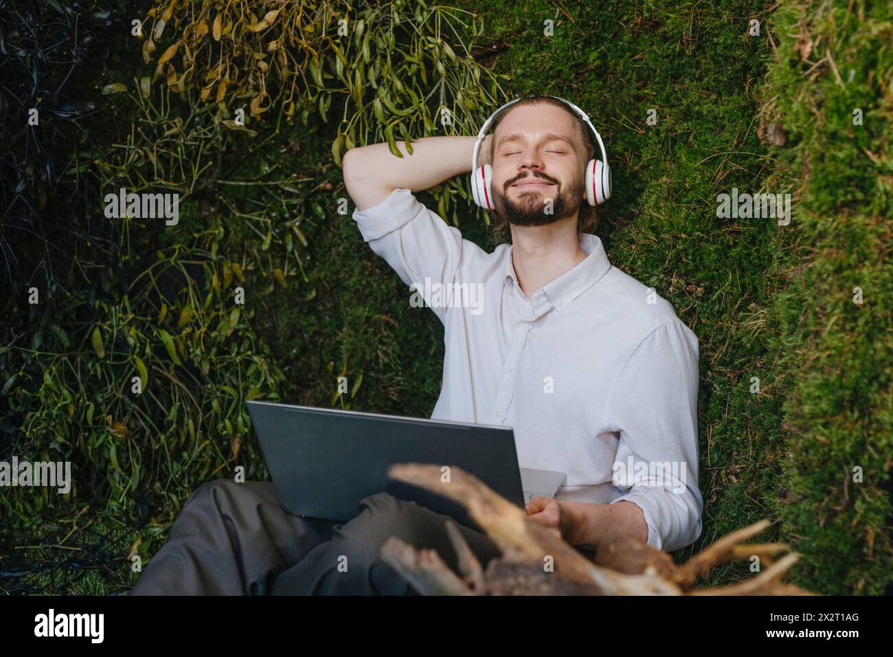 Smiling businessman listening music through wireless headphones and ...