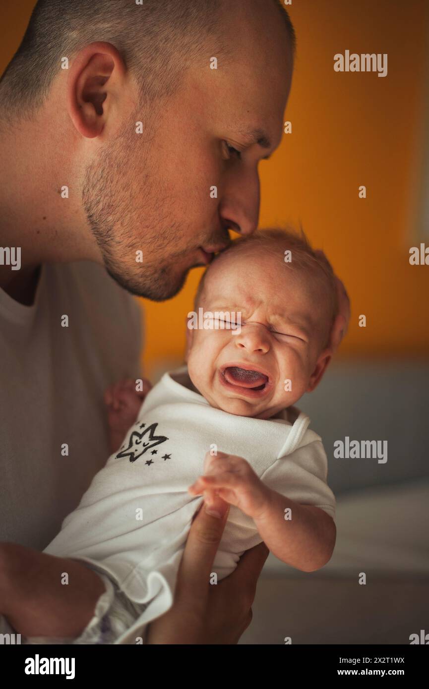 Father kissing crying baby boy at home Stock Photo - Alamy