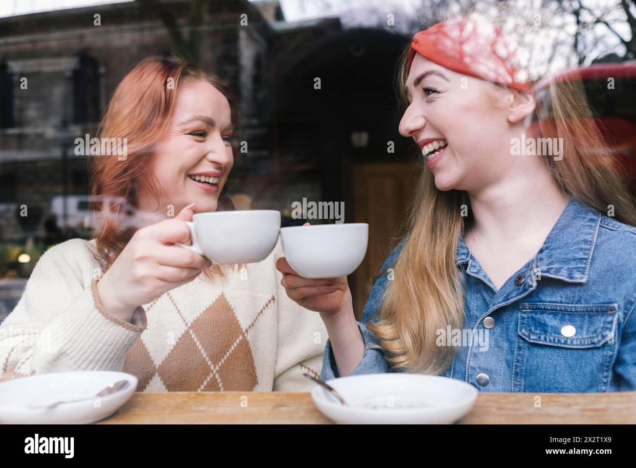 Cheerful friends toasting coffee cups in cafe Stock Photo - Alamy