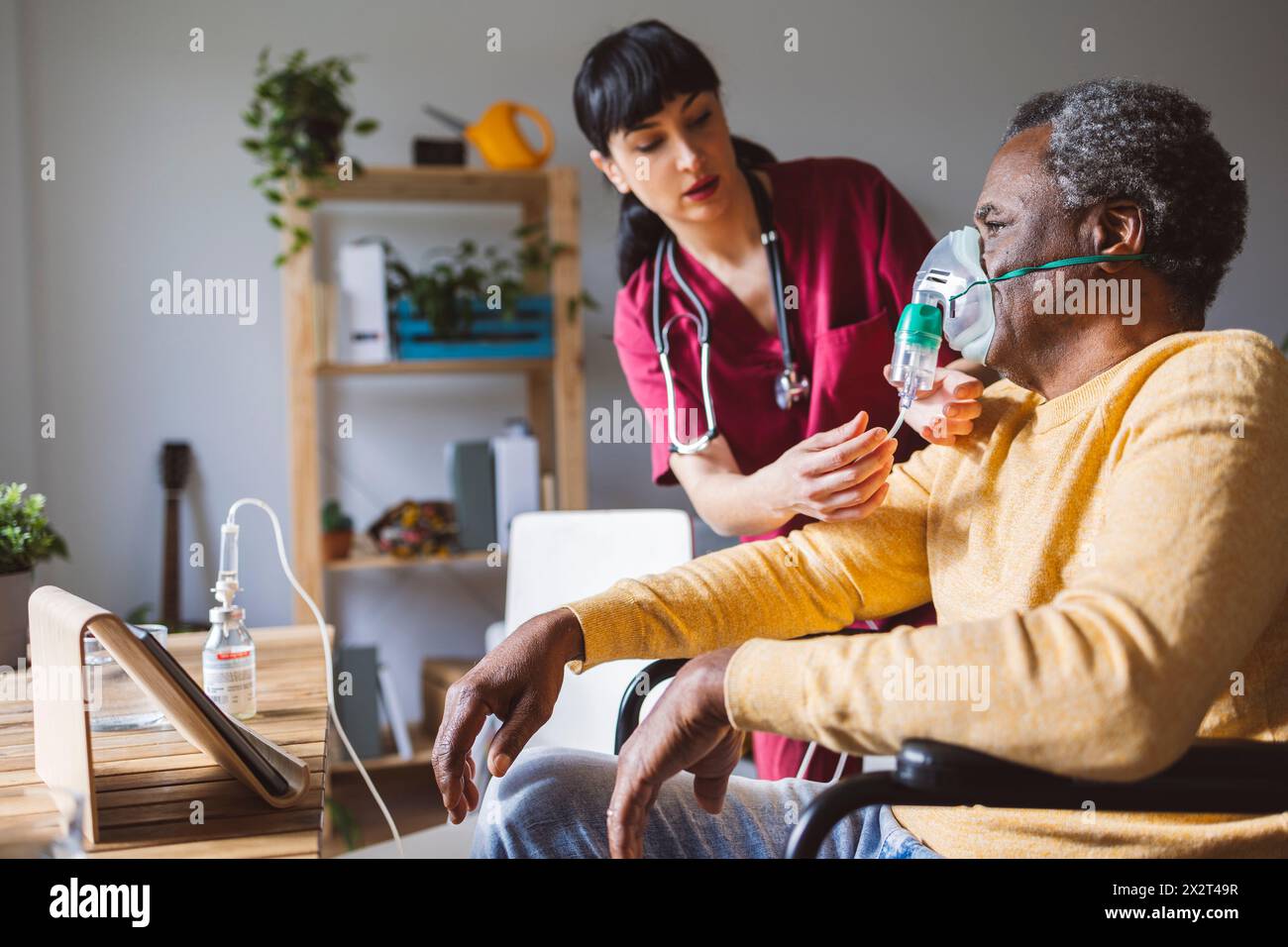 Caregiver putting oxygen mask on senior man sitting in wheelchair at ...