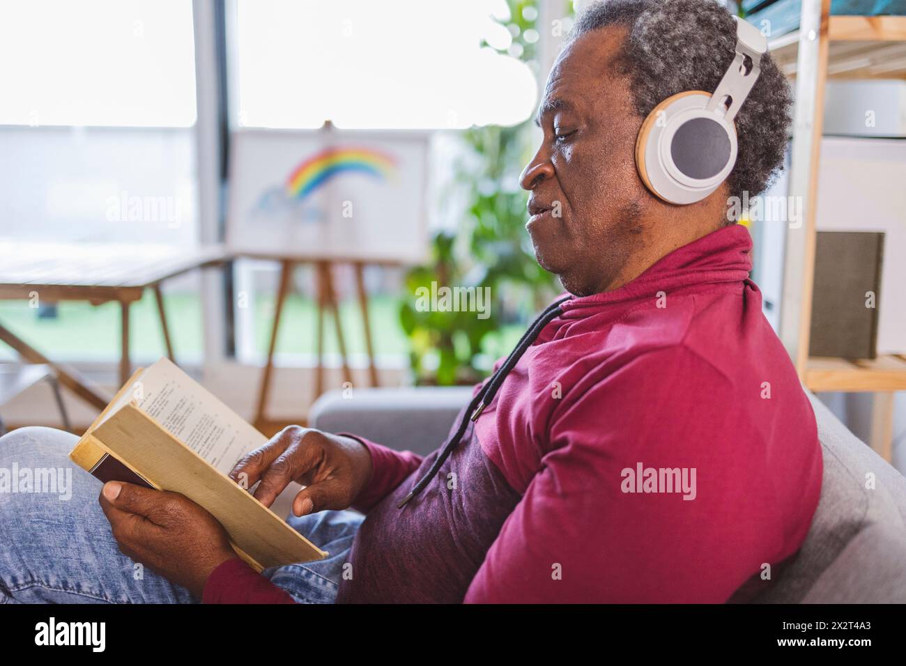 Senior reading book listening music hi-res stock photography and images ...