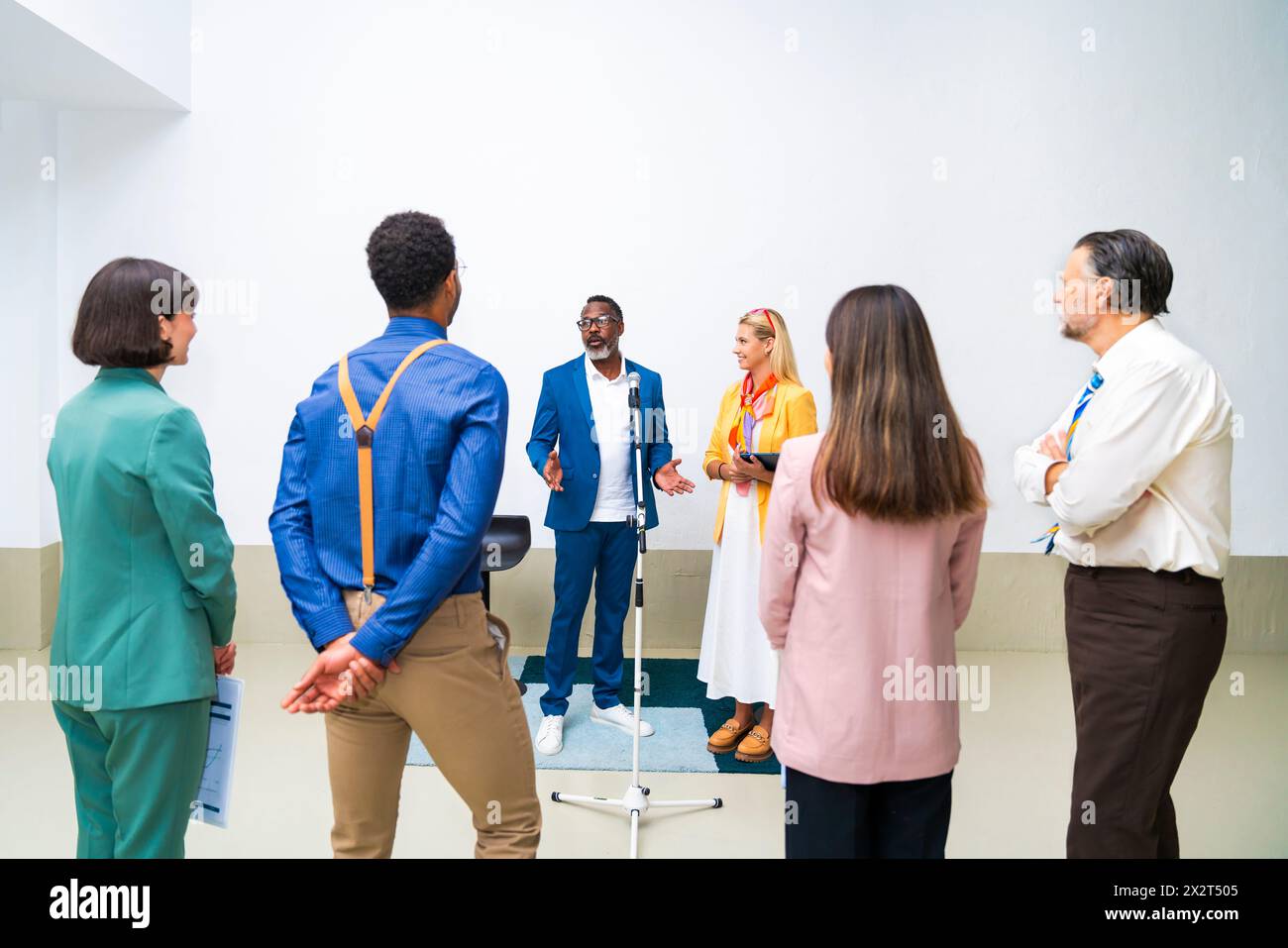 Speaker giving speech to colleagues standing at office Stock Photo - Alamy