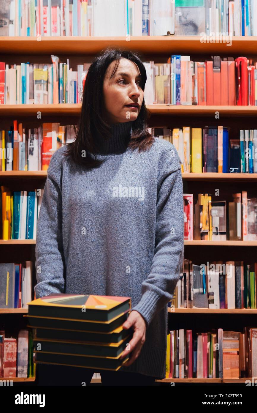 Woman standing and holding stack of books at library Stock Photo - Alamy