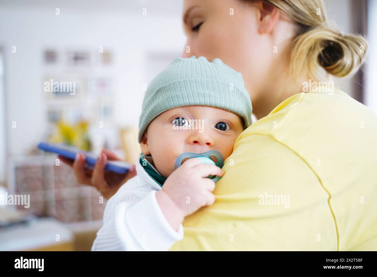 Mother carrying cute boy with pacifier at home Stock Photo - Alamy