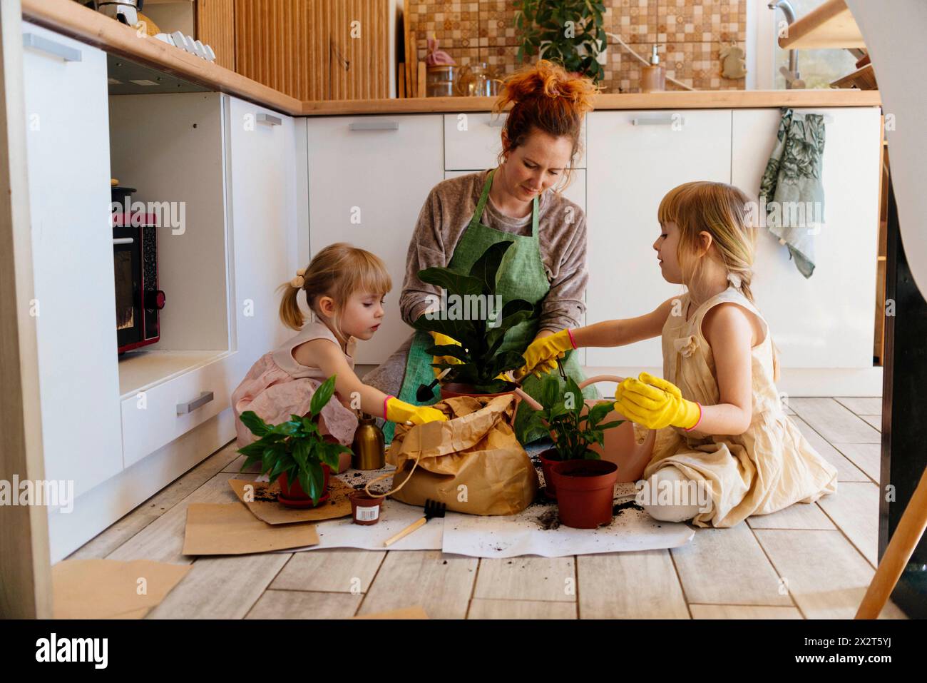 Daughters helping mother in planting plants at home Stock Photo - Alamy