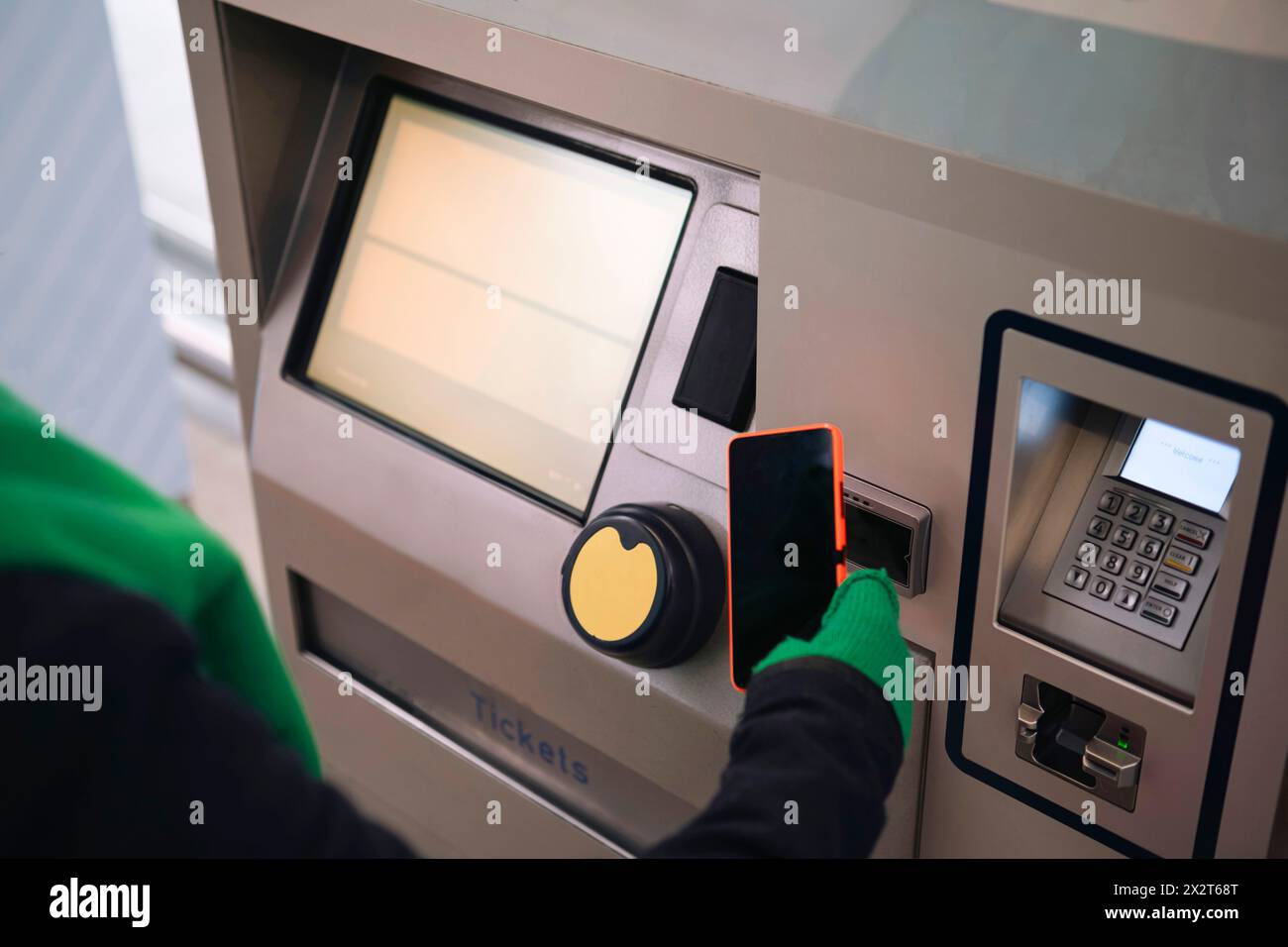 Woman paying for ticket through smart phone near vending machine at ...