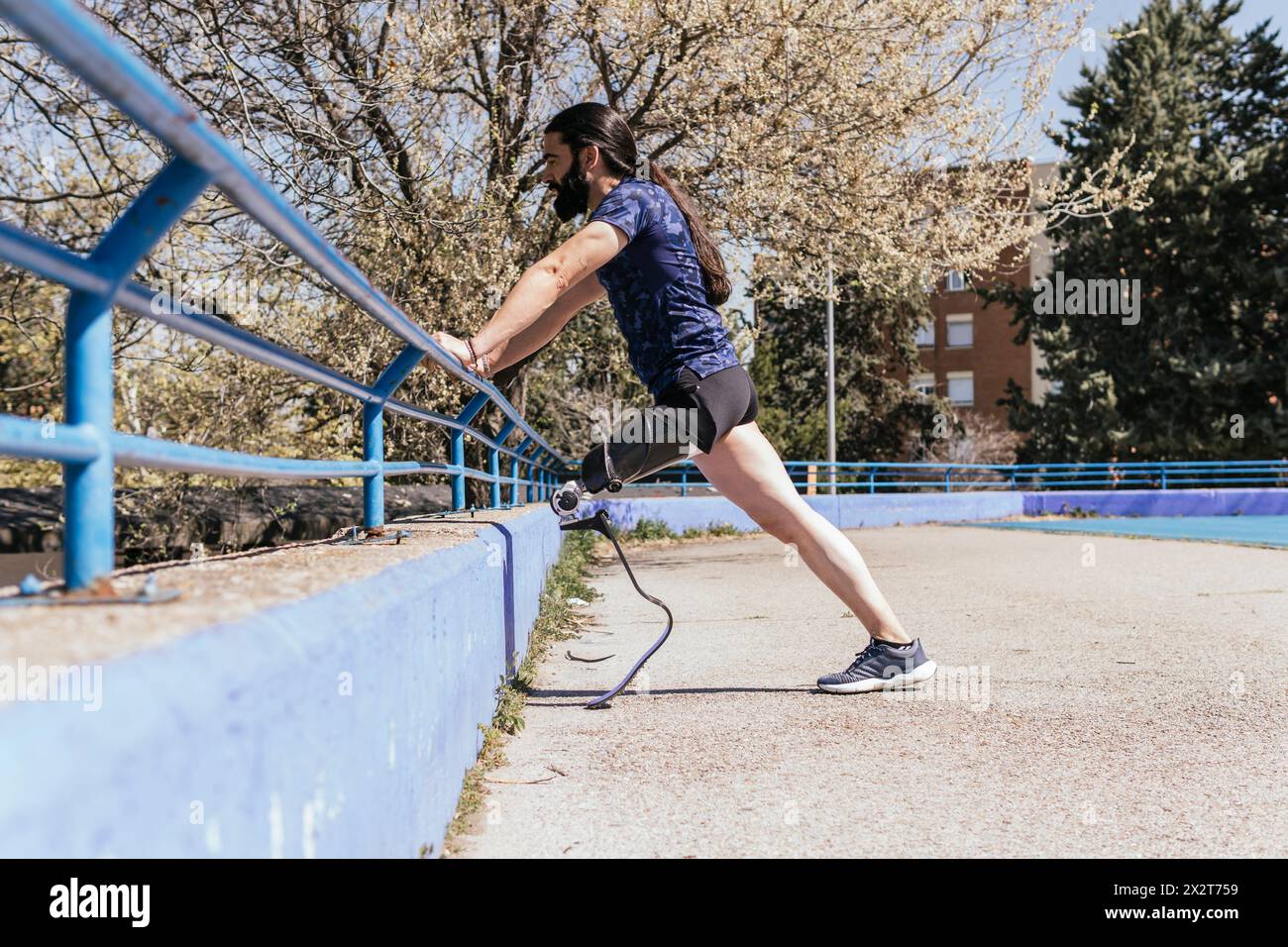 Athlete with prosthetic leg leaning on railing and stretching Stock ...