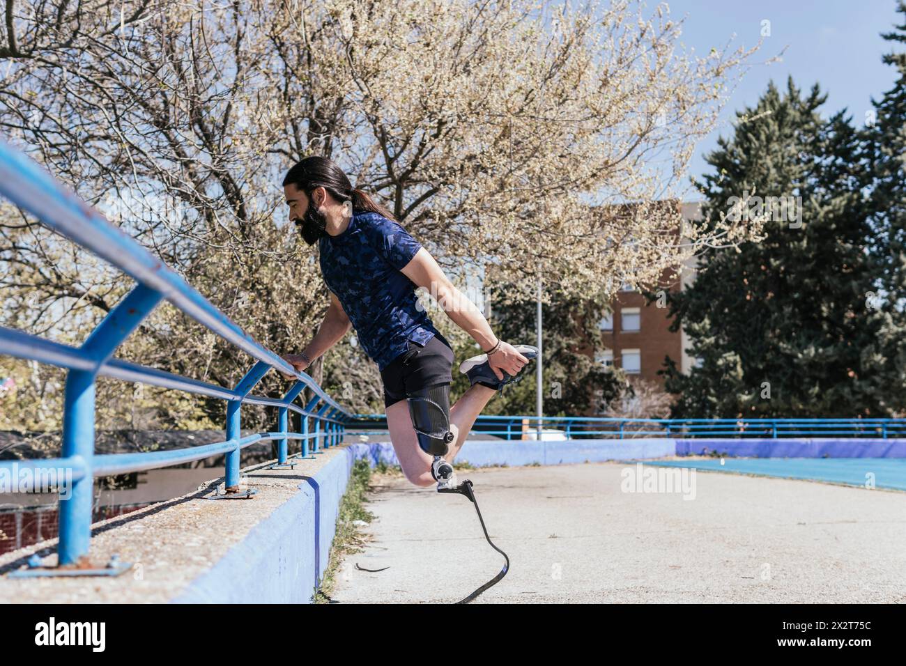 Athlete with artificial leg leaning on railing and stretching Stock ...